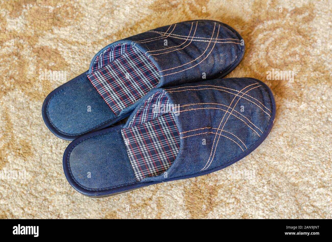Top view of home cozy slippers on a bedside beige rug. Selective focus ...