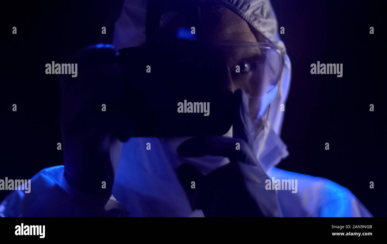 Criminalist taking evidence pictures by camera at crime scene close up ...