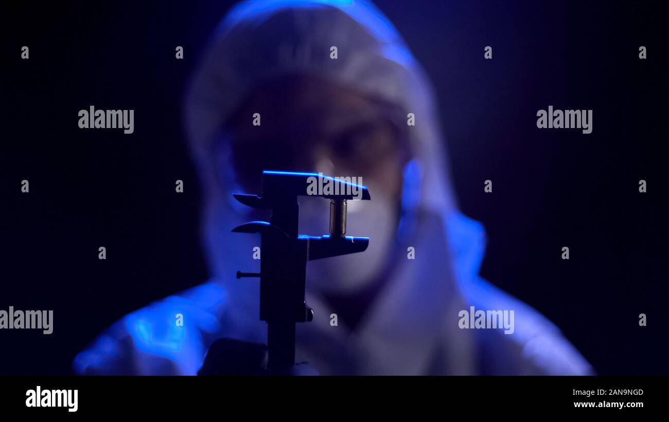 Forensic expert measuring bullet caliber, searching for conclusive ...