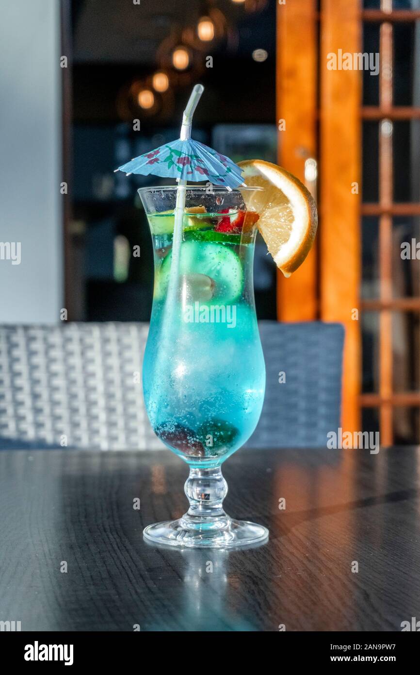 Blue summer cocktail with orange and umbrella Stock Photo - Alamy