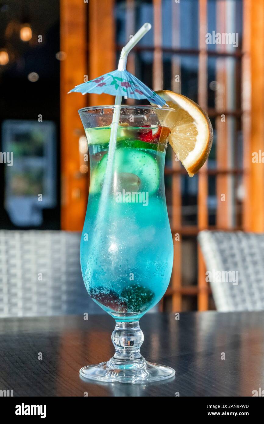 Blue summer cocktail with orange and umbrella Stock Photo - Alamy