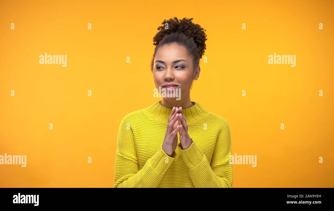 Sly Afro-American female thinking of idea on yellow background, tricky ...