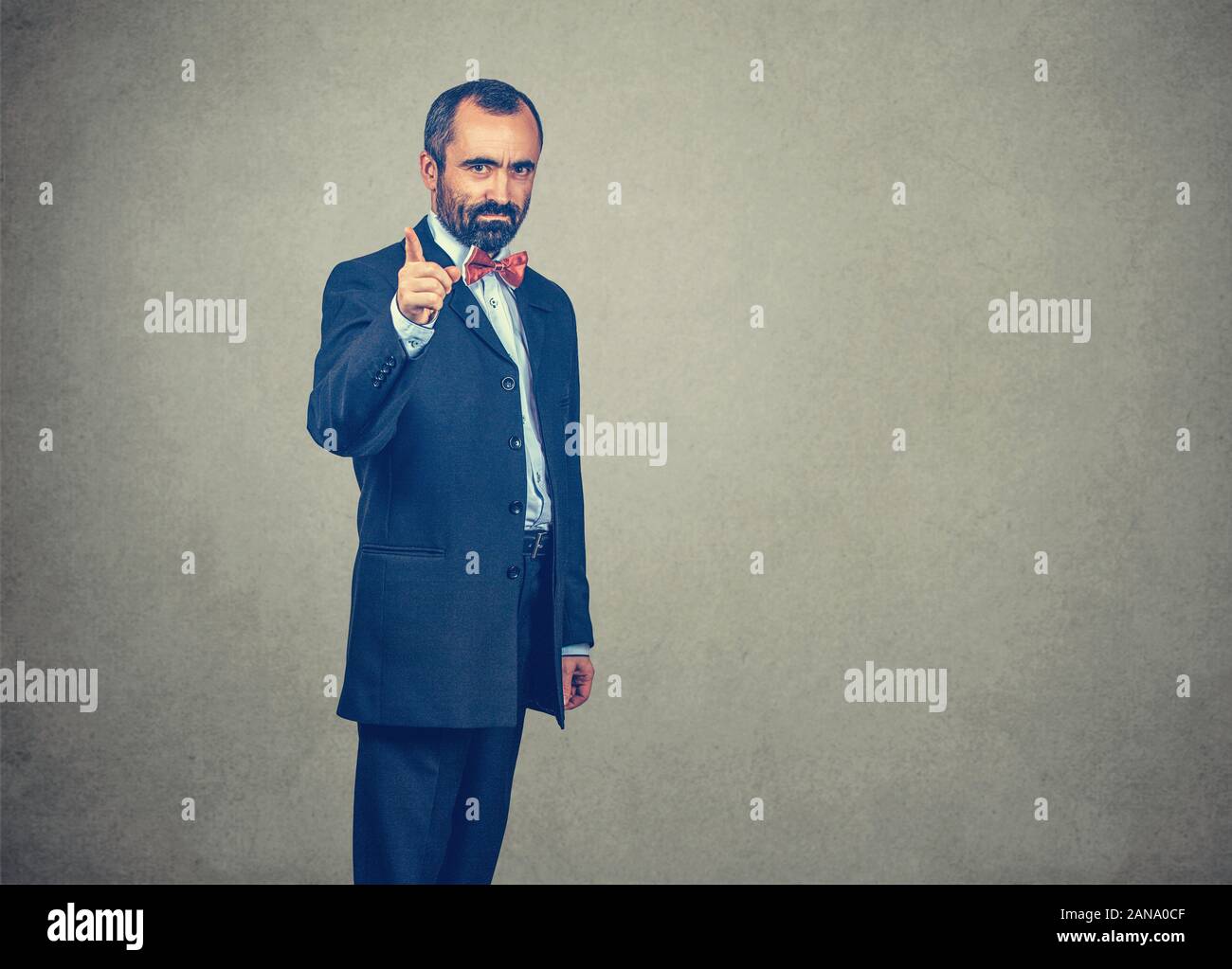Portrait of an angry middle-aged man in formal wear pointing finger at ...