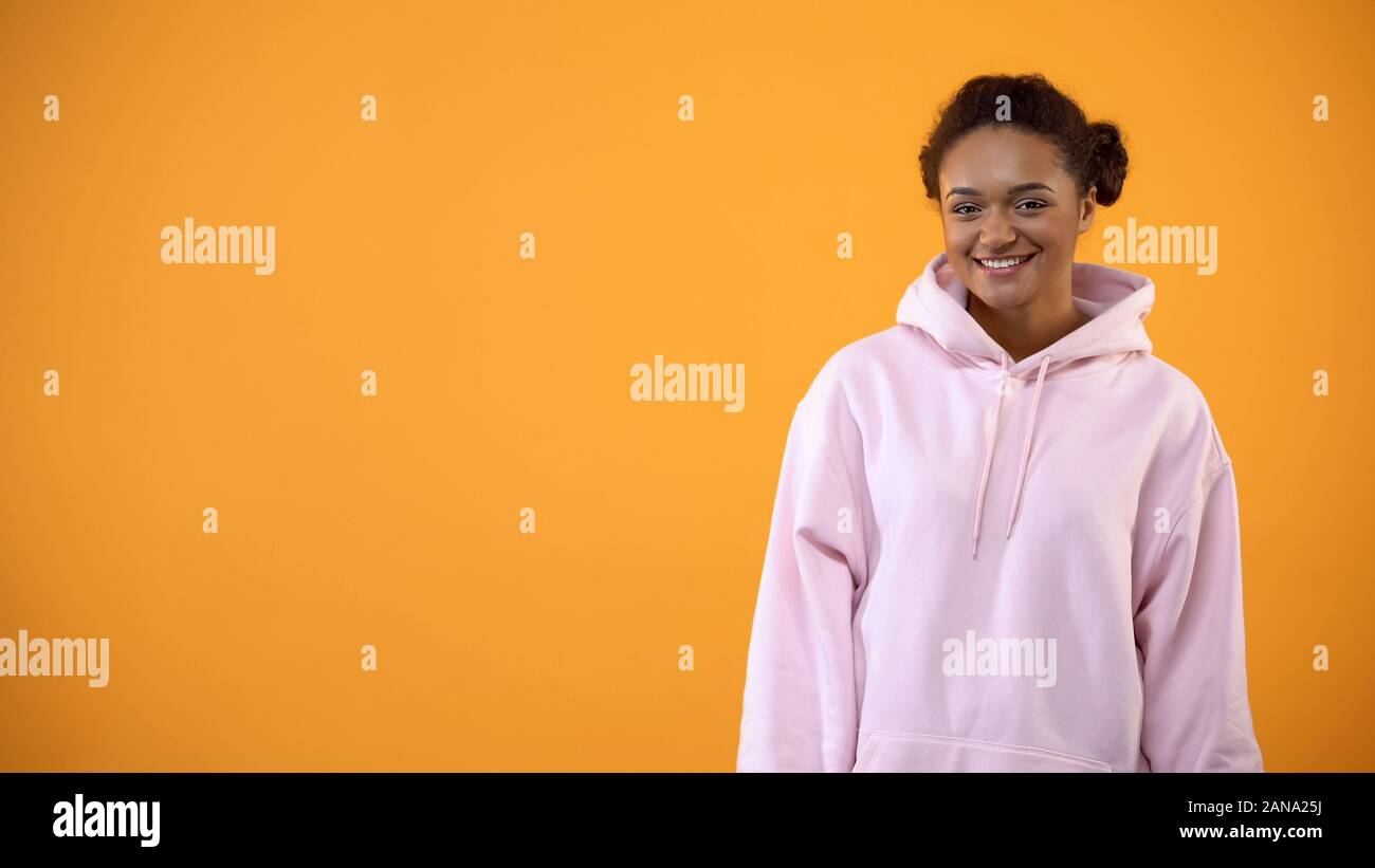 Teenage afro-american female in over-sized hoodie on orange background ...