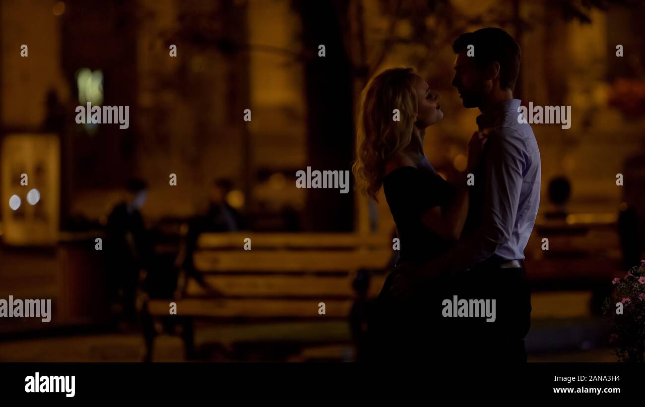 Loving couple hugging and looking at each other on date in night park ...