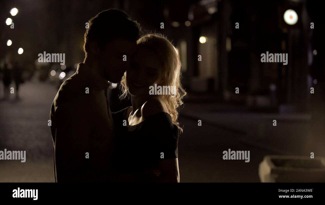 Blond female teasing and cuddling boyfriend in the night street ...