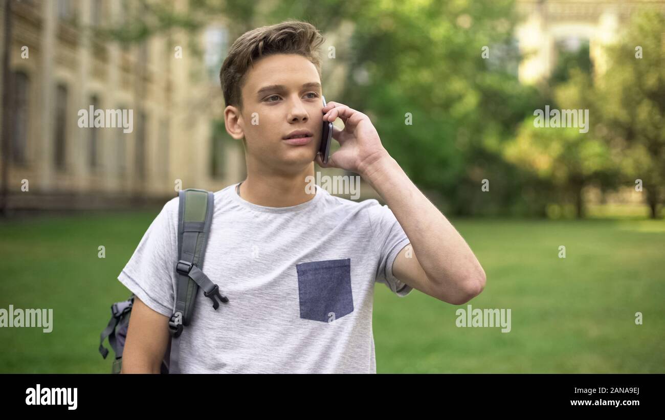 First year student talking on mobile phone with parents in campus ...