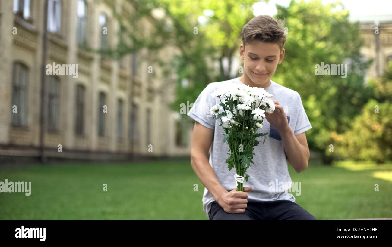 Excited teen boy with bouquet of flowers waiting for girlfriend ...