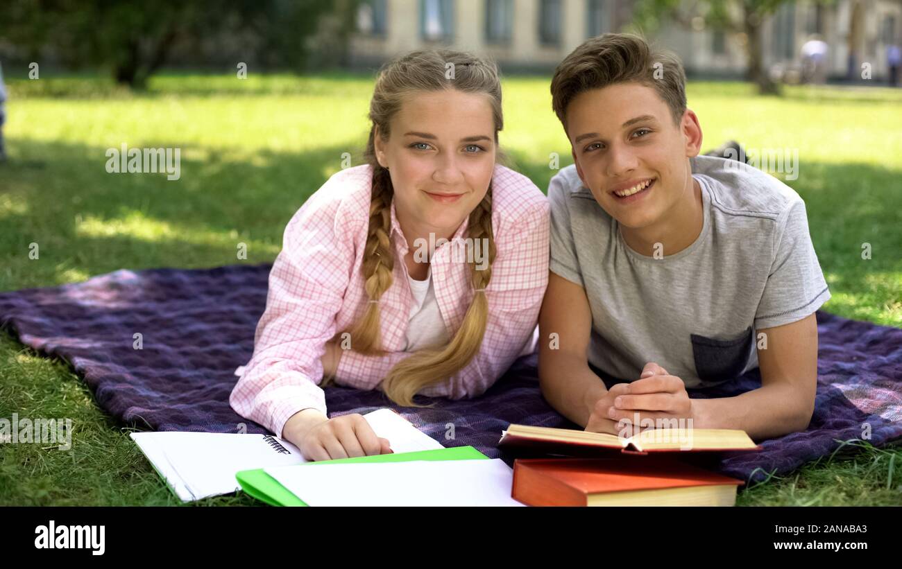 Students looking at camera, lying on plaid near university campus ...
