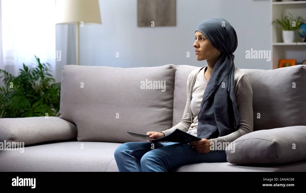 Sad woman with cancer looking in window holding xray in hands, fighting ...