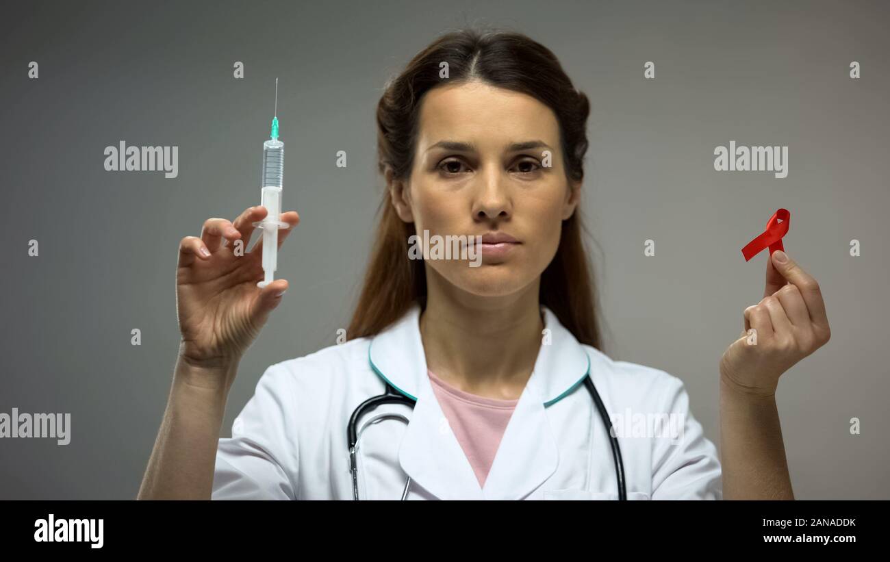Woman doctor showing red ribbon and syringe AIDS prevention campaign ...