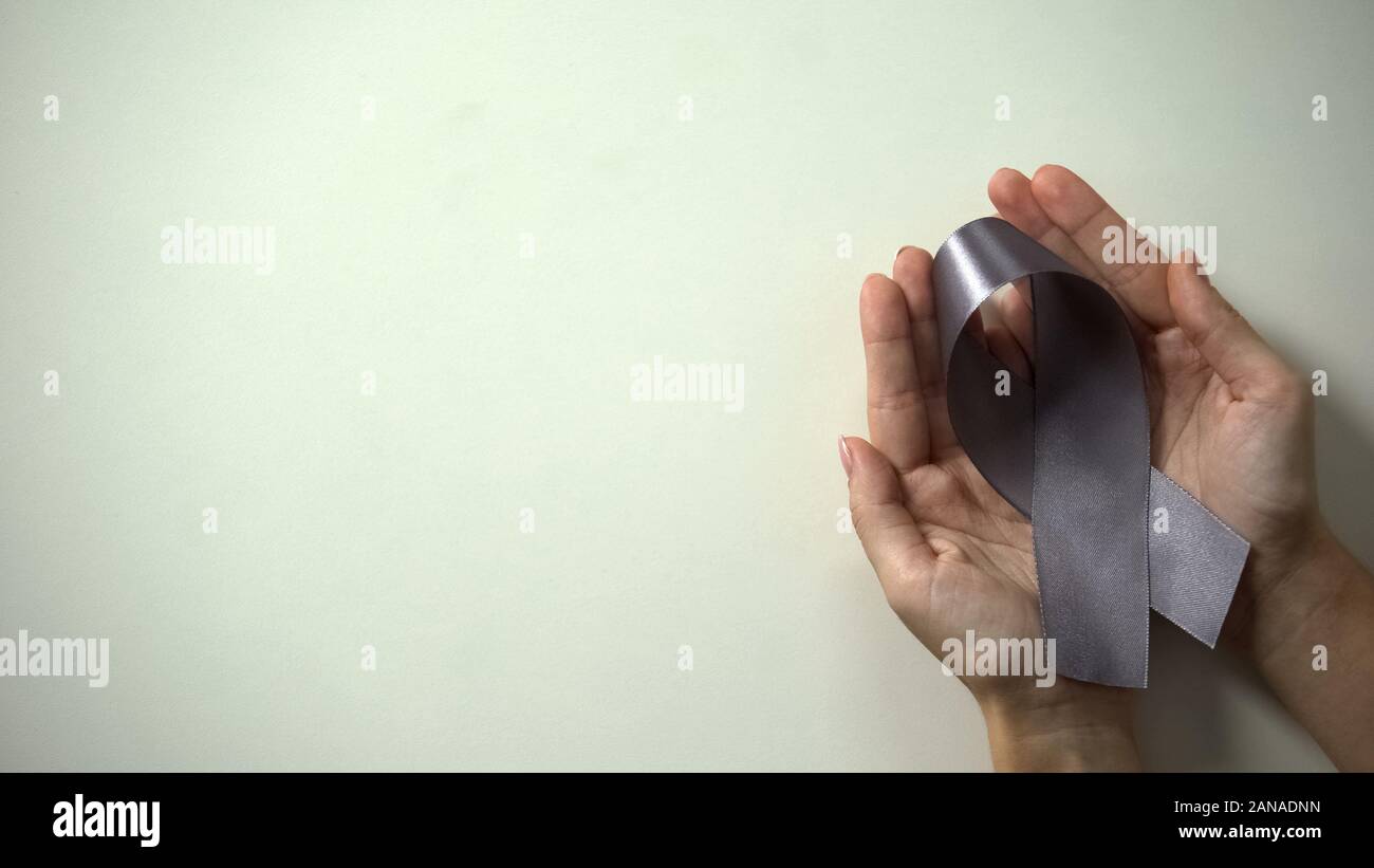 Gray ribbon in lady hands, brain cancer awareness, tumor treatment ...