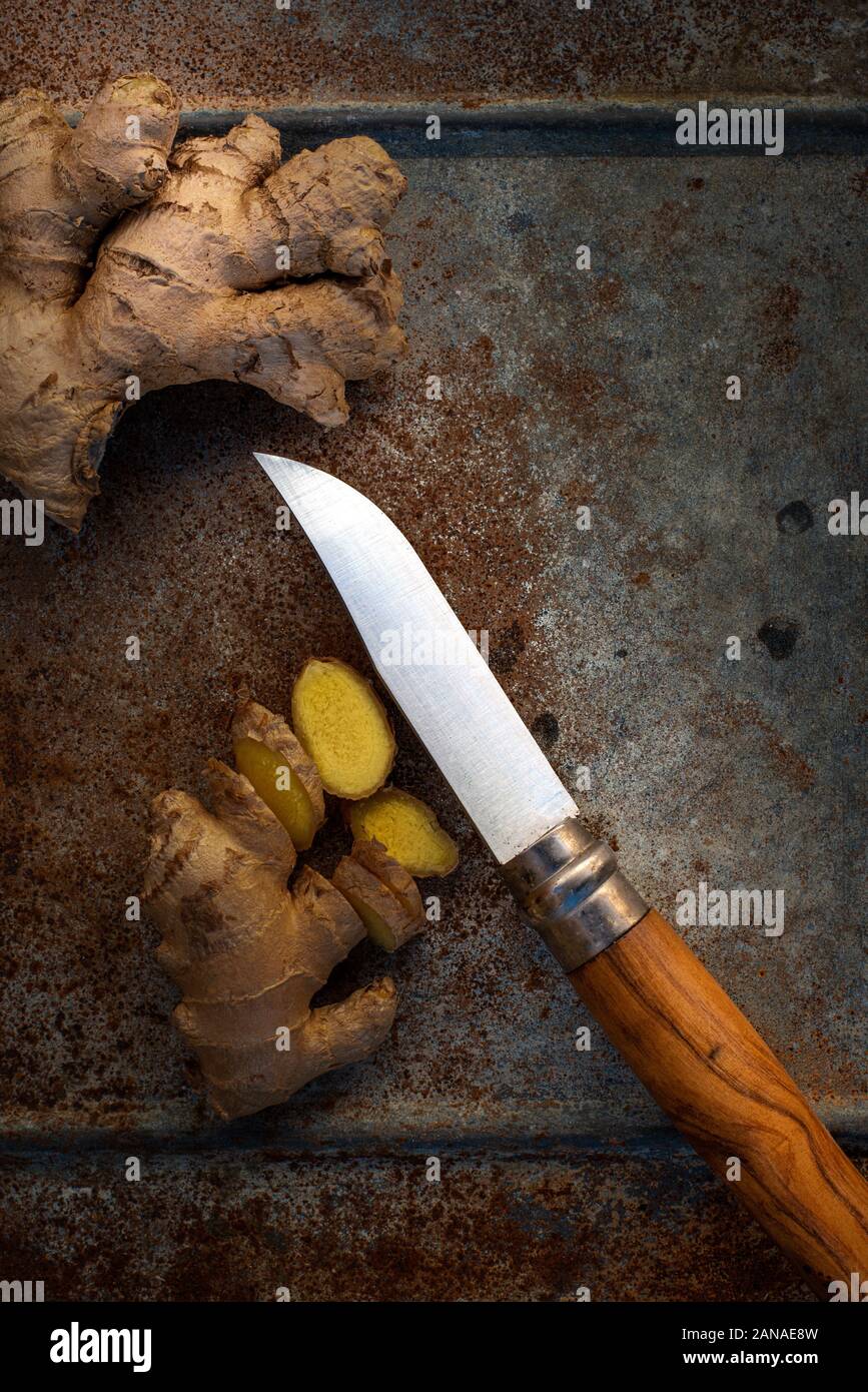 Cut and whole Ginger with knife on rustic background Stock Photo - Alamy
