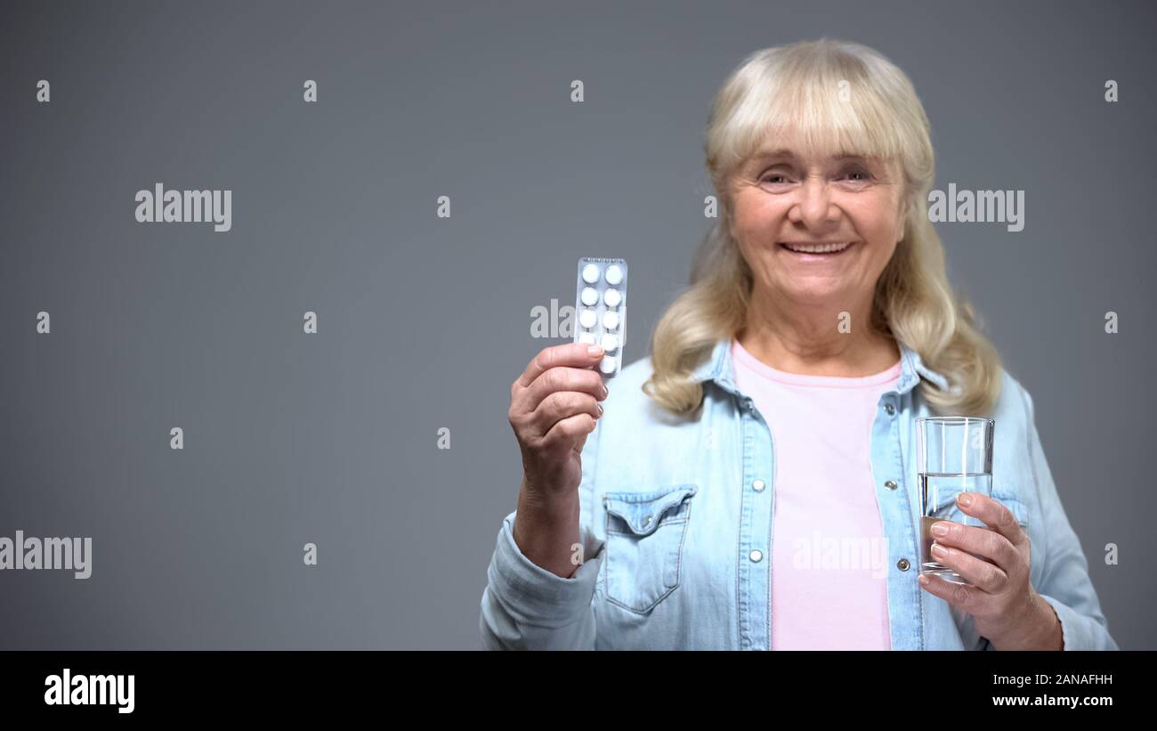 Smiling aged lady showing pills medication quality, immunity ...