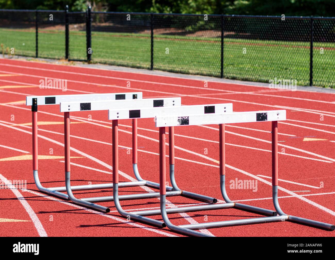 Four hurdles are together on a red track for athletes to do form and ...