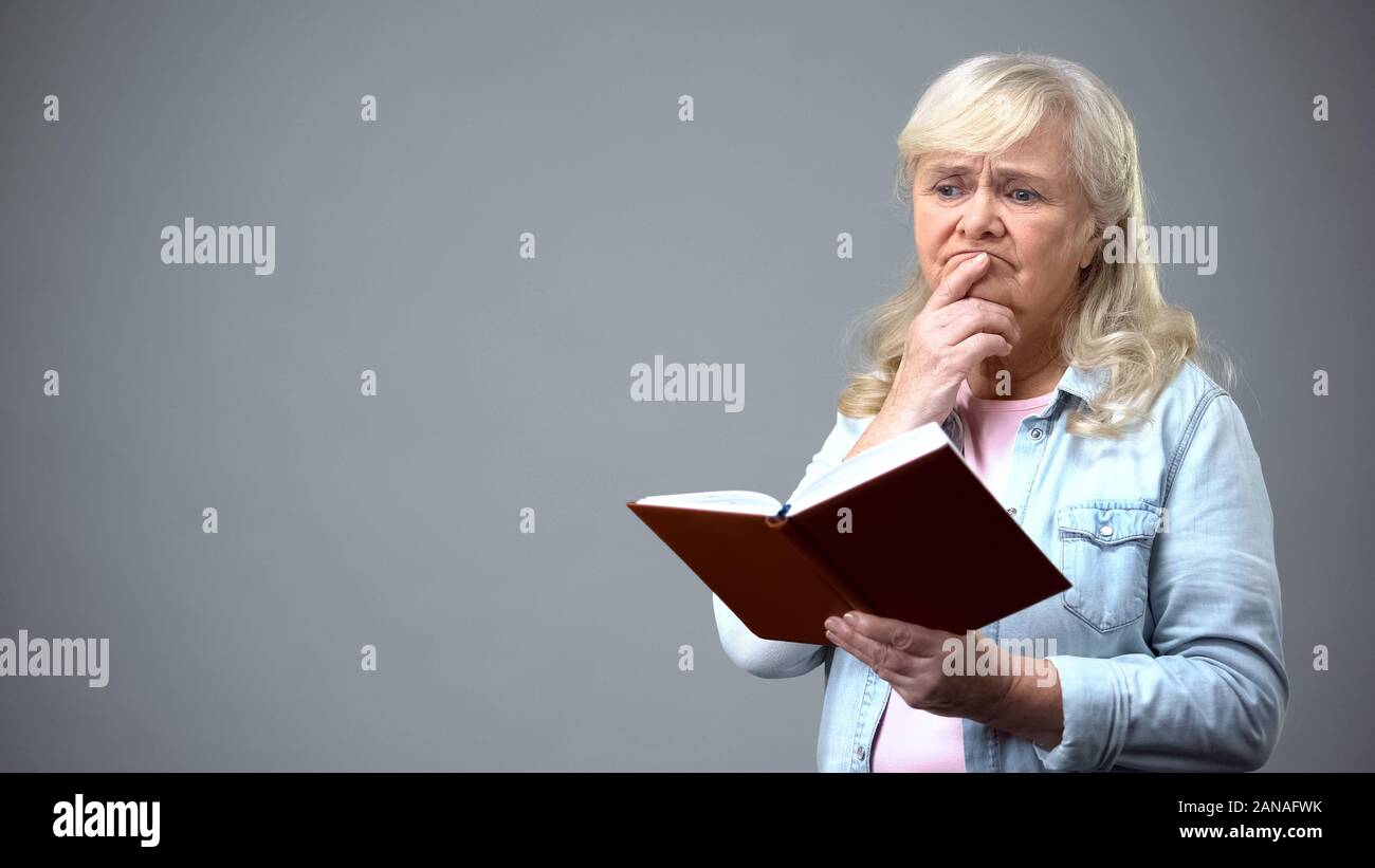 Senior woman thinking over information from book, lifelong self ...