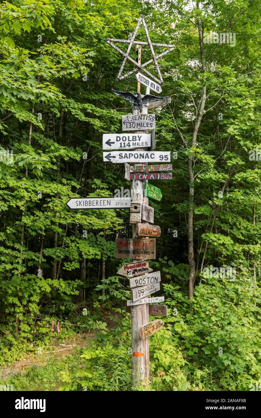 A wooden sign post has arrows with how many miles it is to other states ...