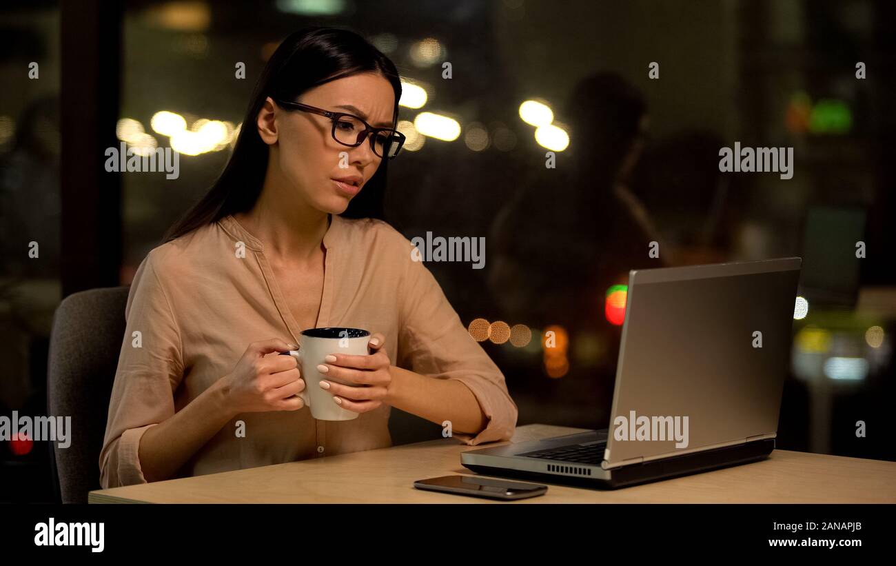 Sad female worker reading email holding cup of tea, job difficulties ...