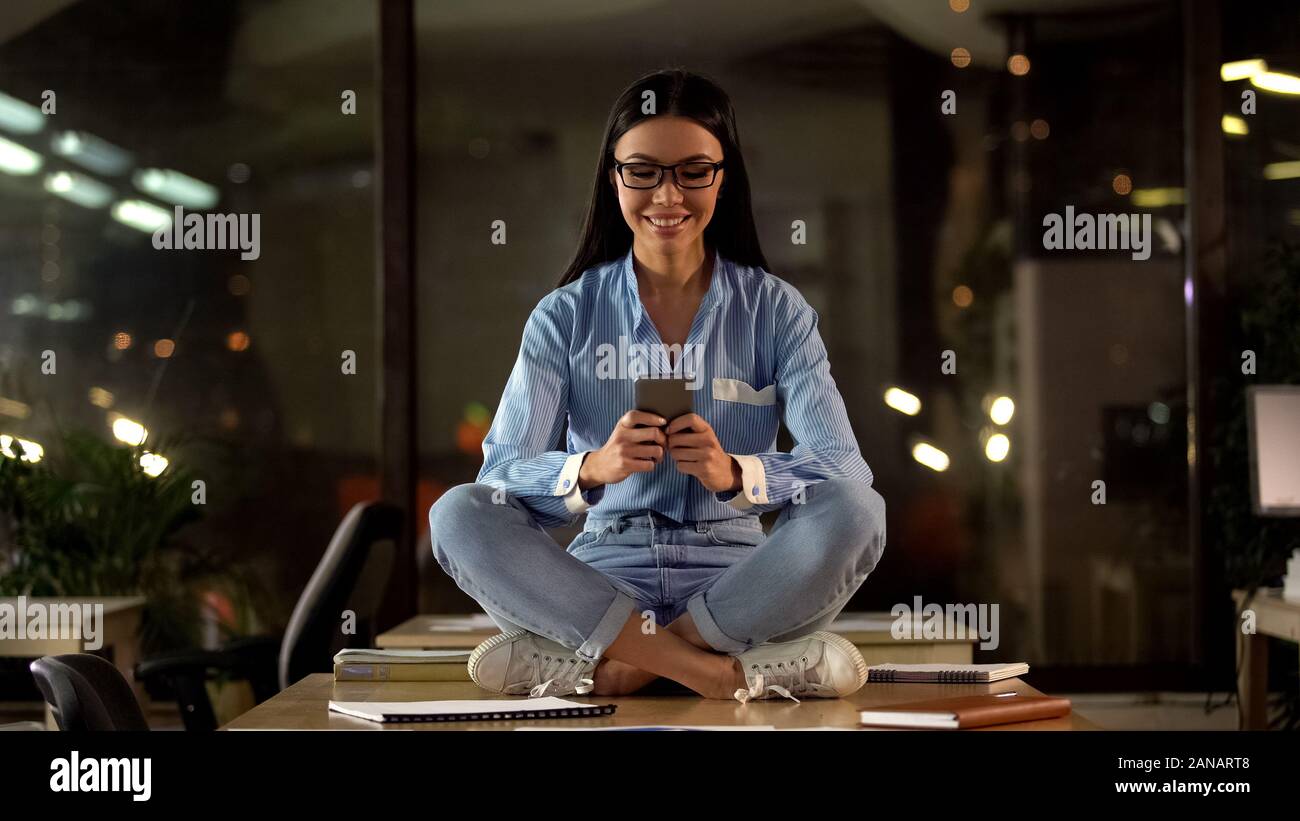 Happy woman in lotus position using cell phone in office, break time at work Stock Photo - Alamy