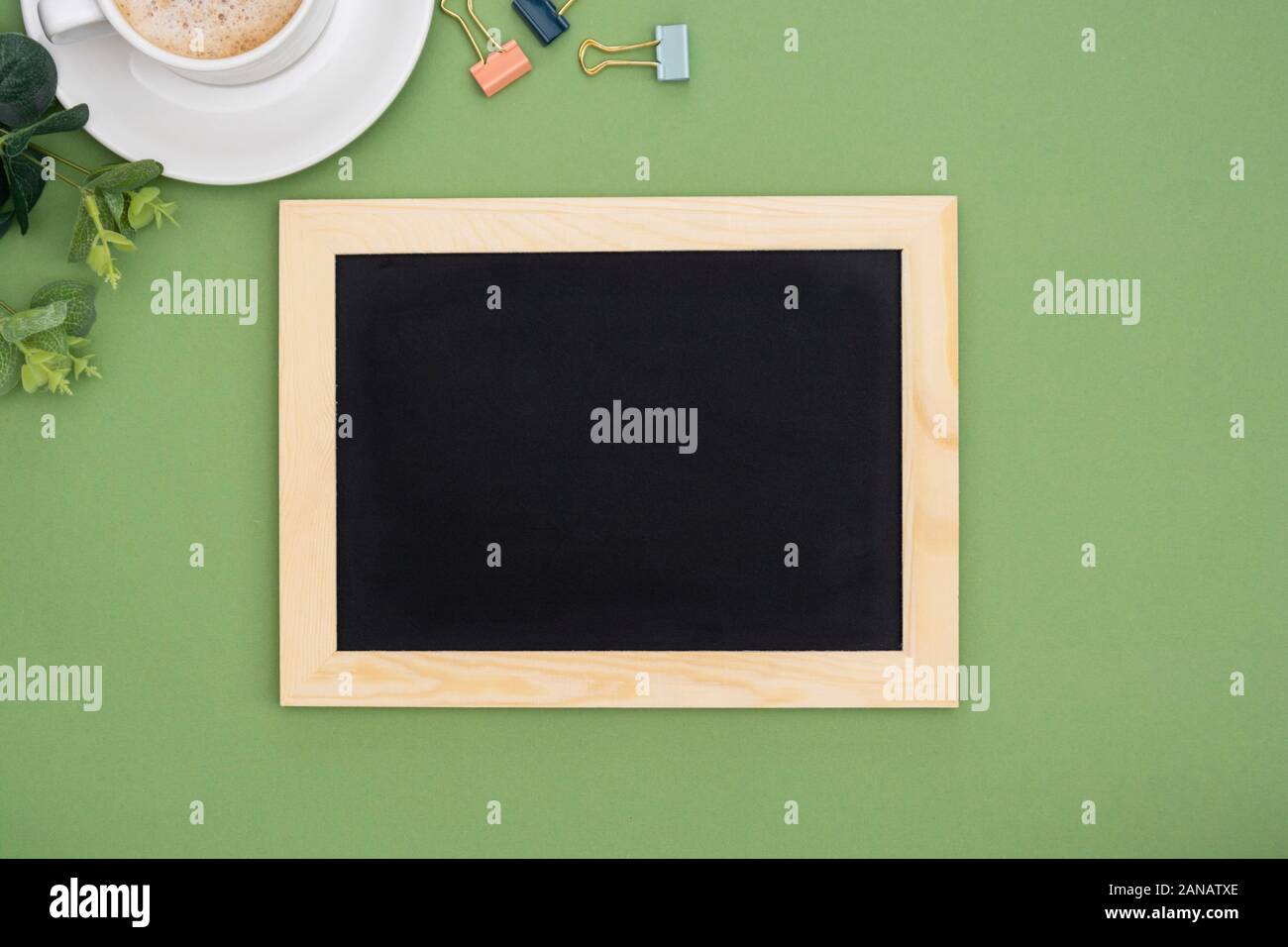 Top view of chalkboard frame with coffee cup, over green background ...
