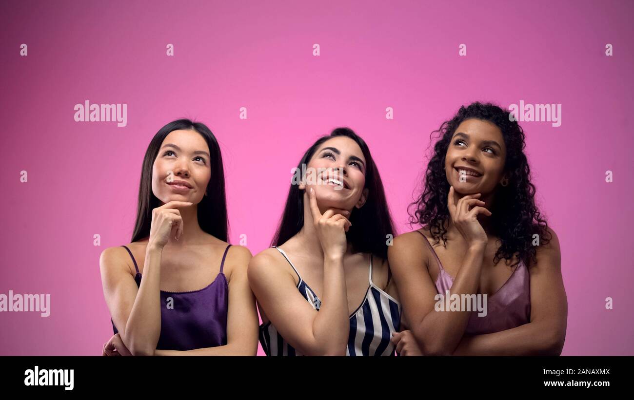 Three beautiful women thinking and smiling, dreaming about luxury life ...