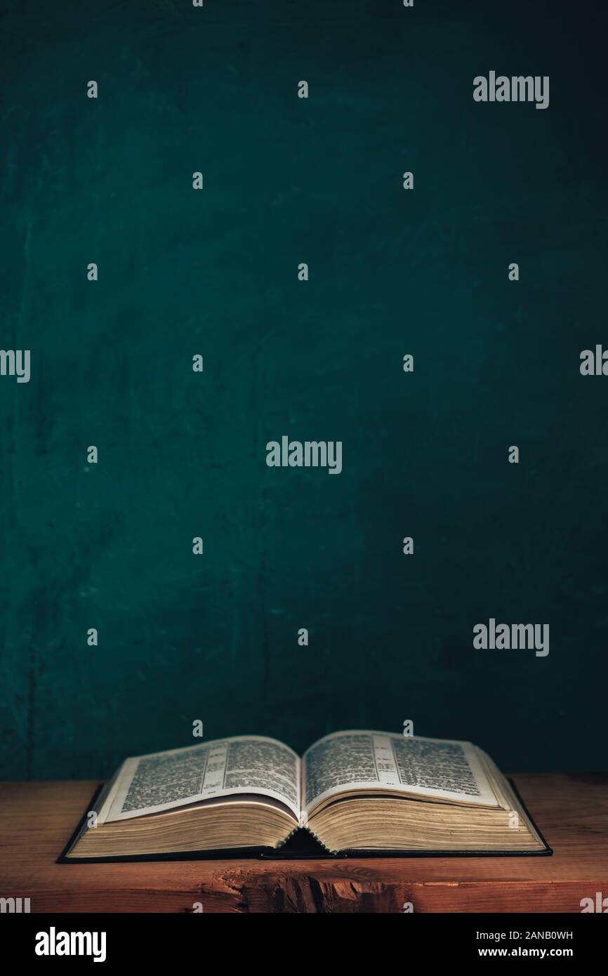 Open bible on a red old wooden table. Beautiful green wall background ...