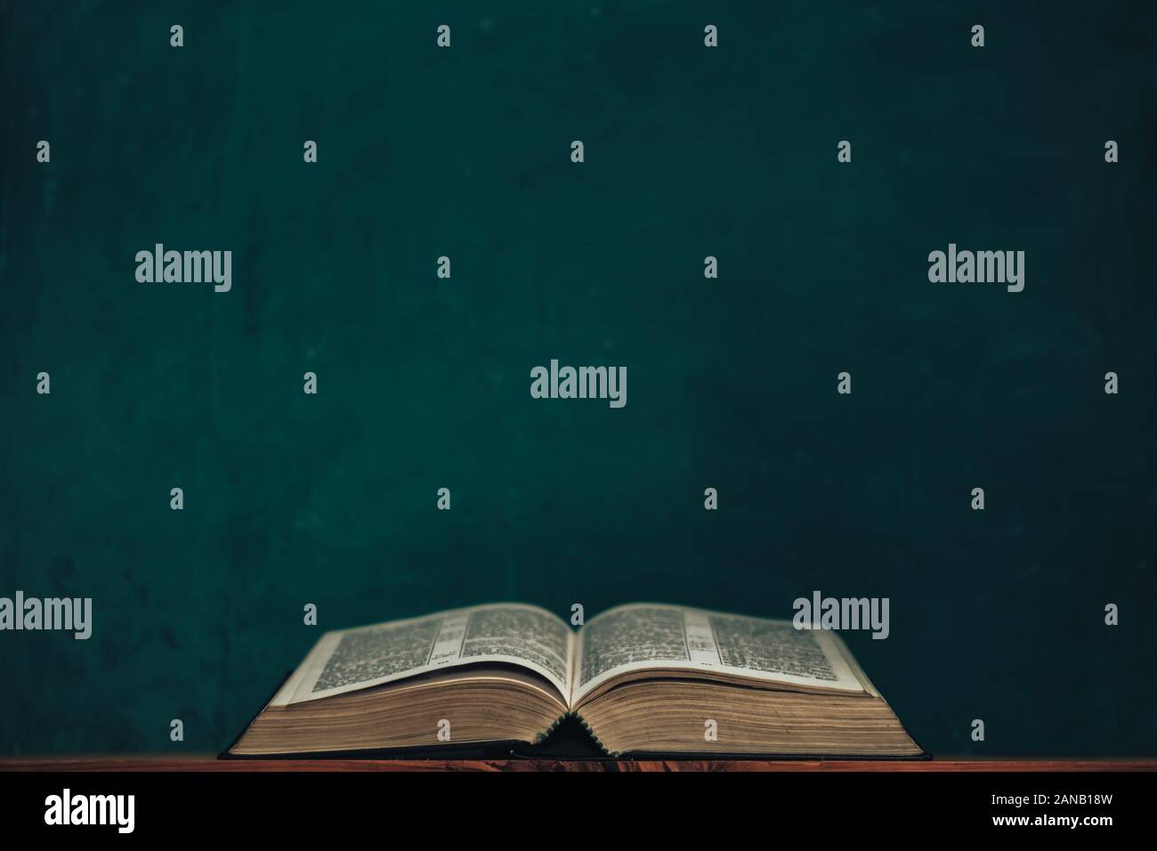 Open bible on a red old wooden table. Beautiful green wall background ...