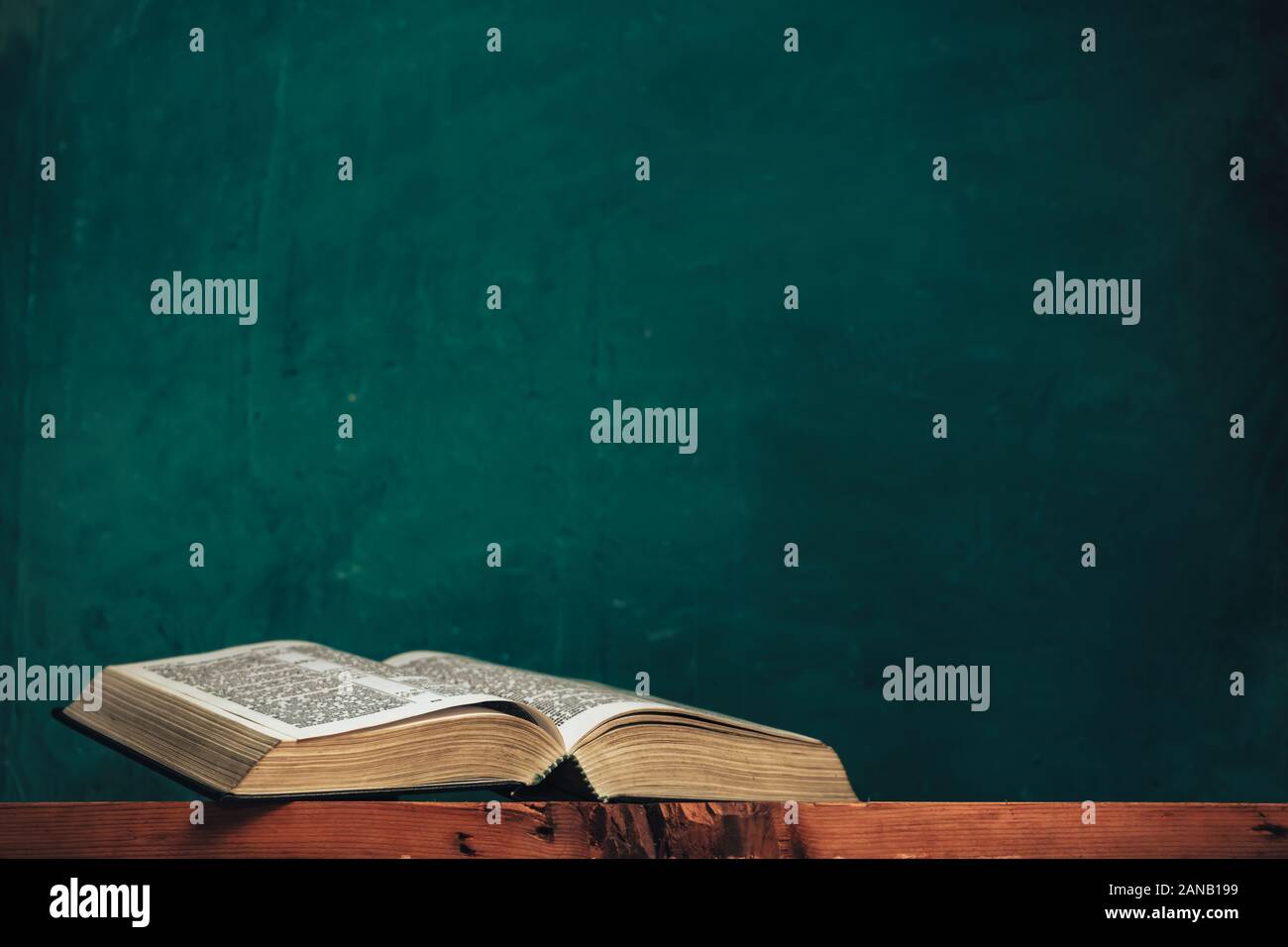 Open bible on a red old wooden table. Beautiful green wall background ...