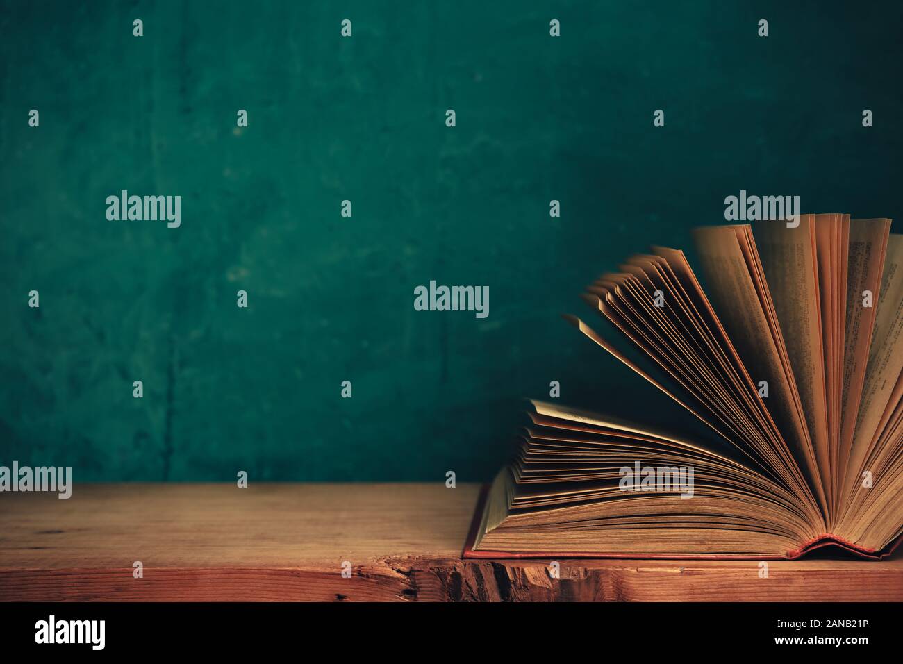 Close up Open old book on a old oak wooden table and green wall ...