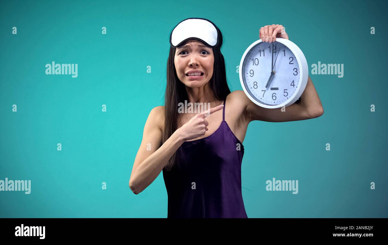 Frustrated girl pointing at 7 am on clock face, overslept and getting ...