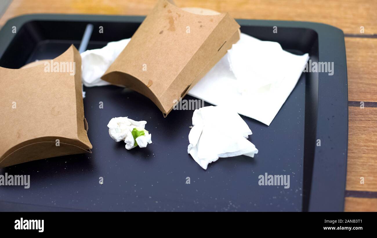 Empty fast food packages and crumpled tissue on plastic tray, self ...
