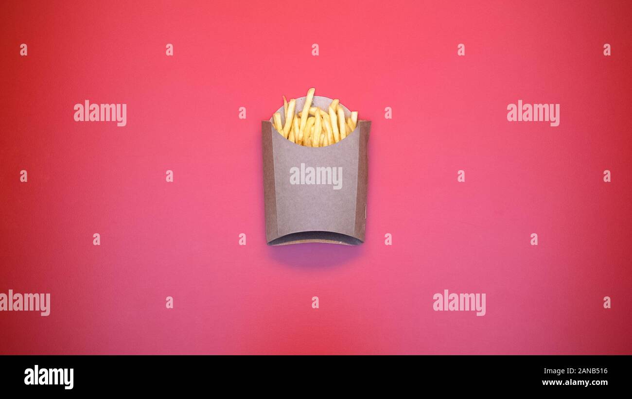 Crispy french fries in carton package on pink background, fast food ...