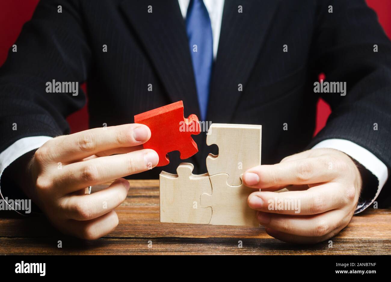 Businessman connects a red puzzle to the assembly. Business model ...