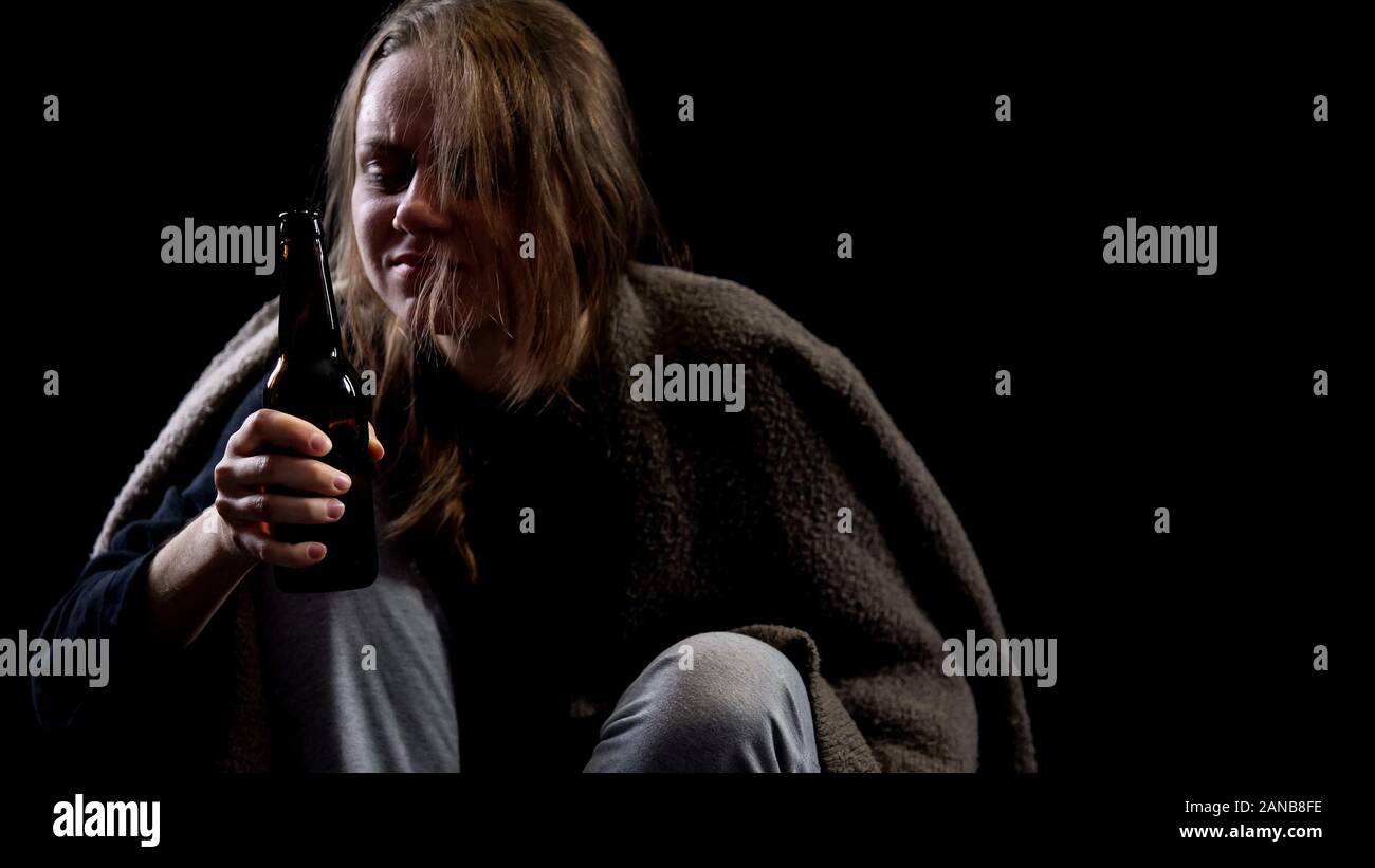 Miserable alcoholic woman drinking beer on black background, harmful ...