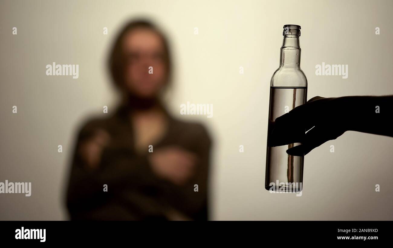 Hand holding vodka bottle offering alcohol, will power, rehabilitation ...