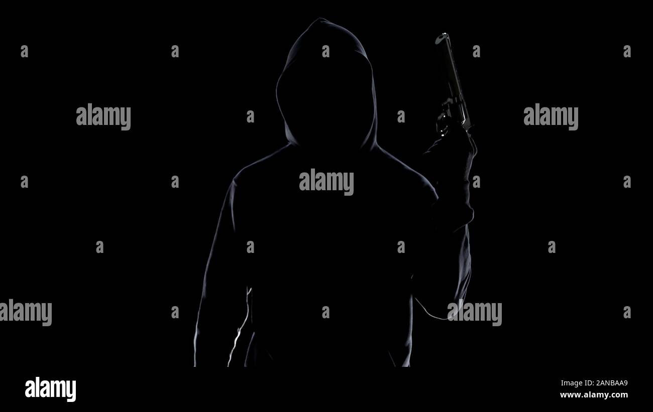 Silhouette of serial killer in hoodie threatening with gun, preparing ...