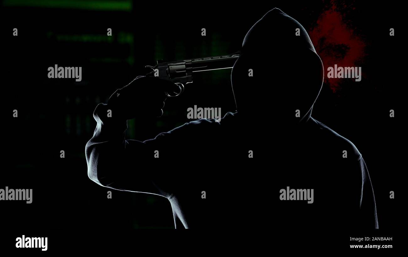 Silhouette of hacker shooting himself with gun on computer code ...