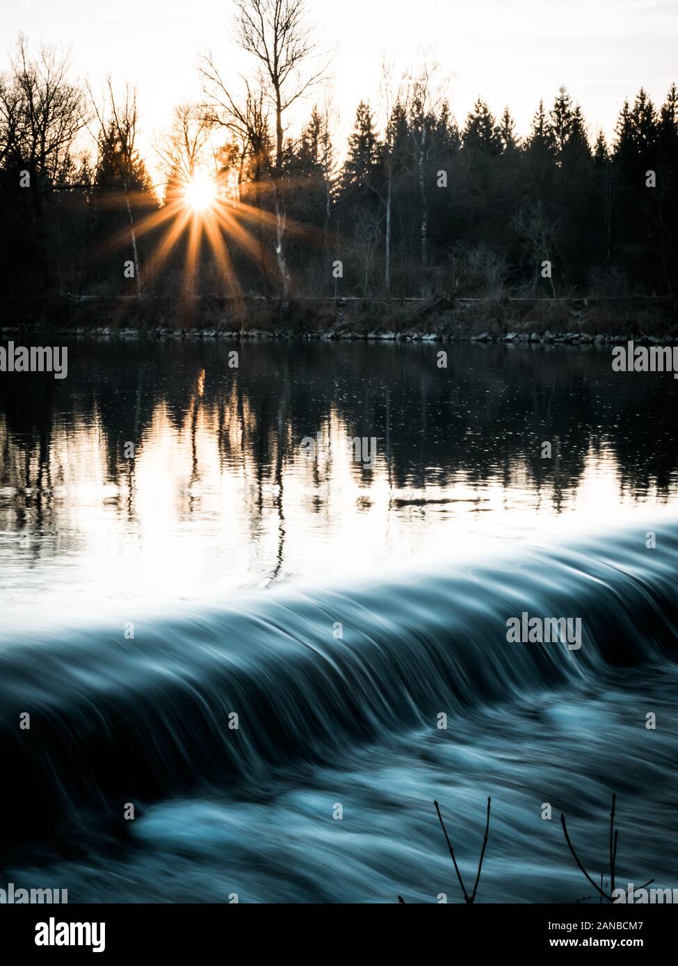Water flowing over a weir during sunset with sun rays in the winter, Augsburg Stock Photo - Alamy