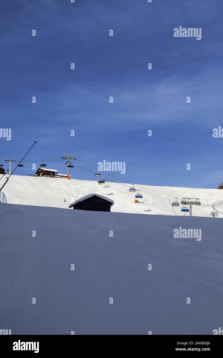 Snowy ski track prepared with snow grooming machine, chair lift and ...