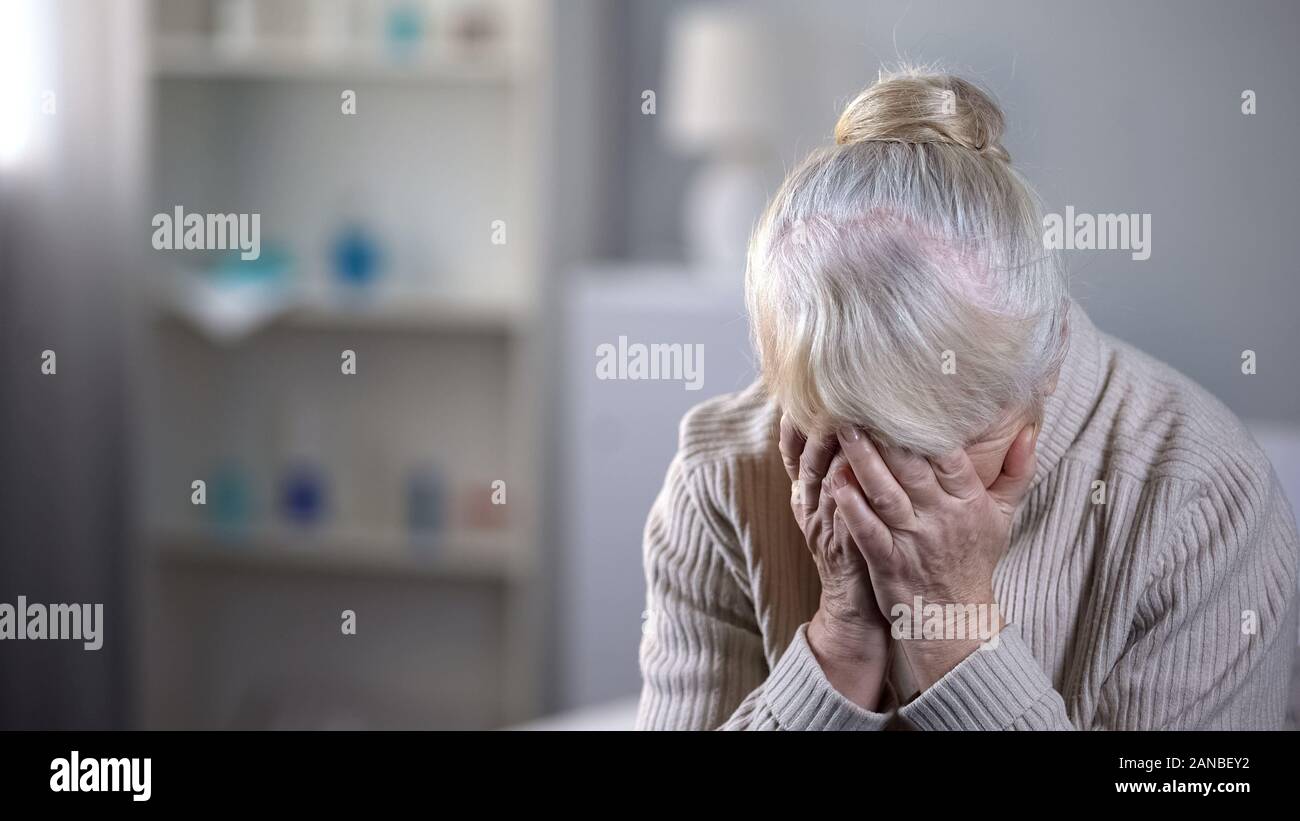 Unhappy elderly lady sitting alone in living room and deeply crying ...