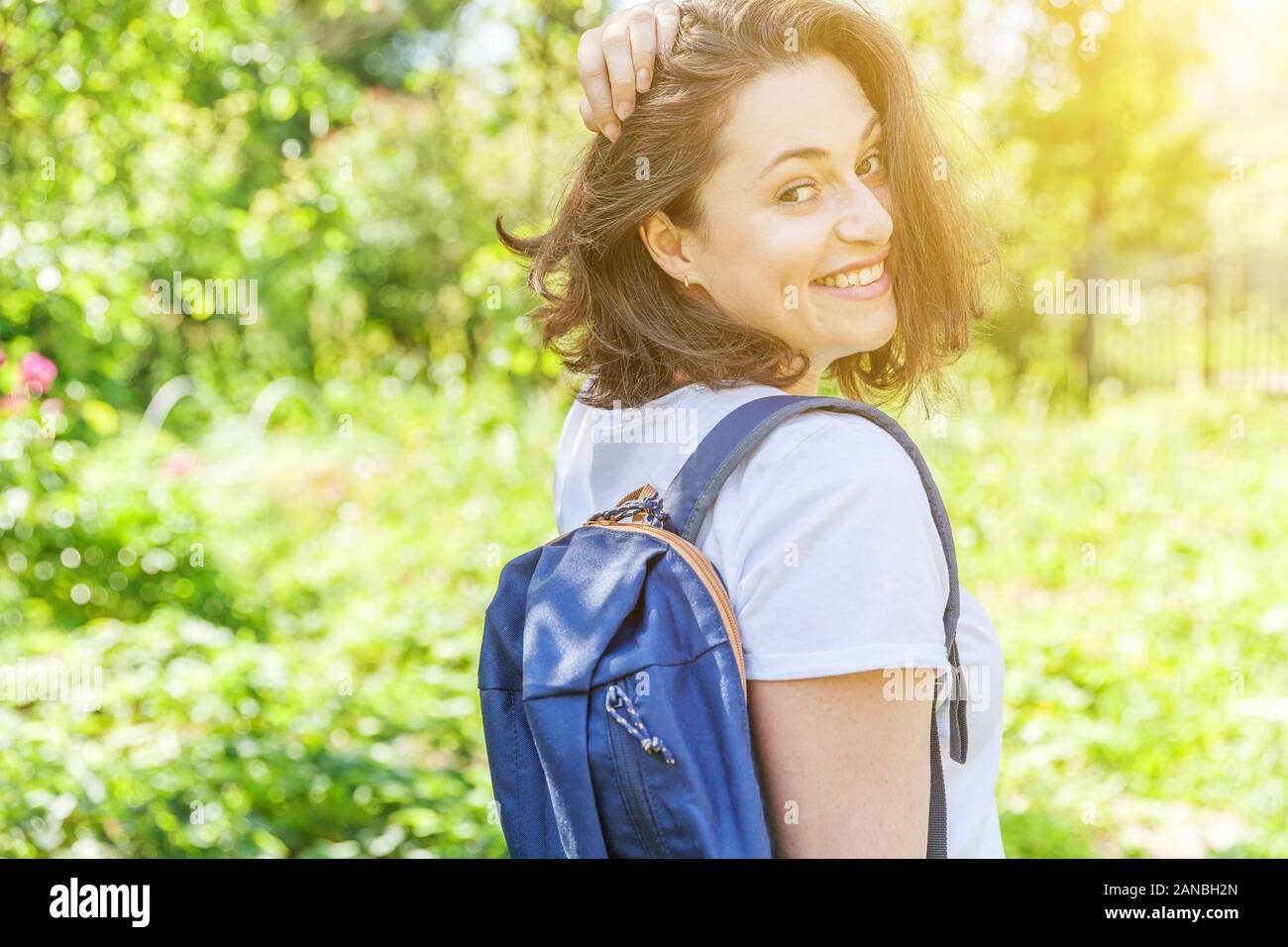 Happy positive student girl with backpack smiling on green park ...
