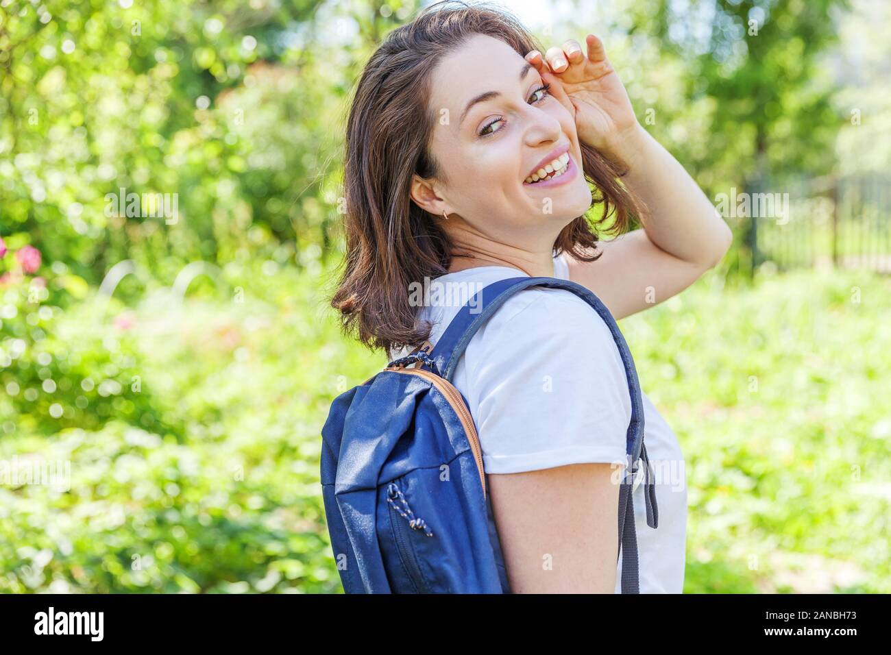 Happy positive student girl with backpack smiling on green park ...