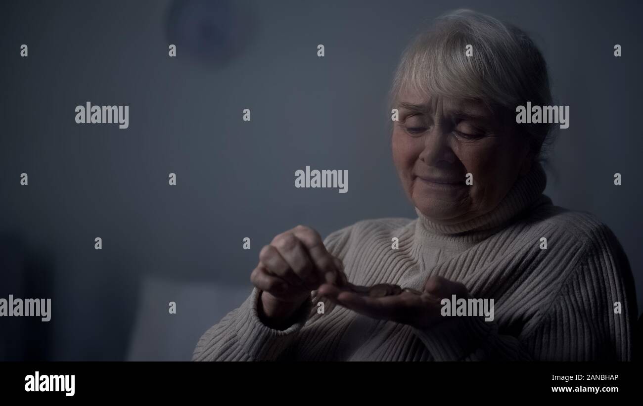 Crying elderly woman counting coins in hand, social insecurity, pension ...