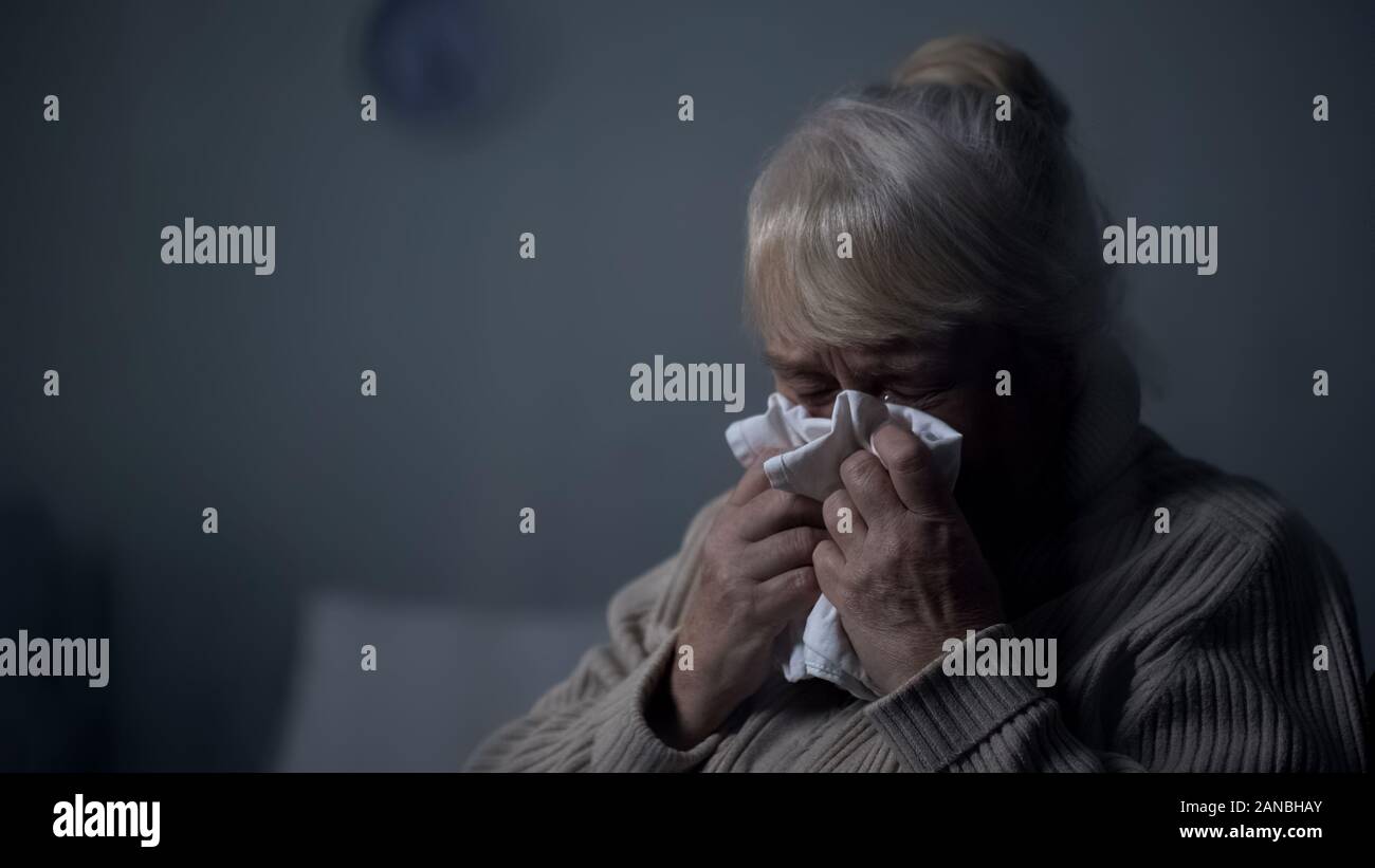 Desperate elderly female deeply crying in dark room, hospice loneliness ...