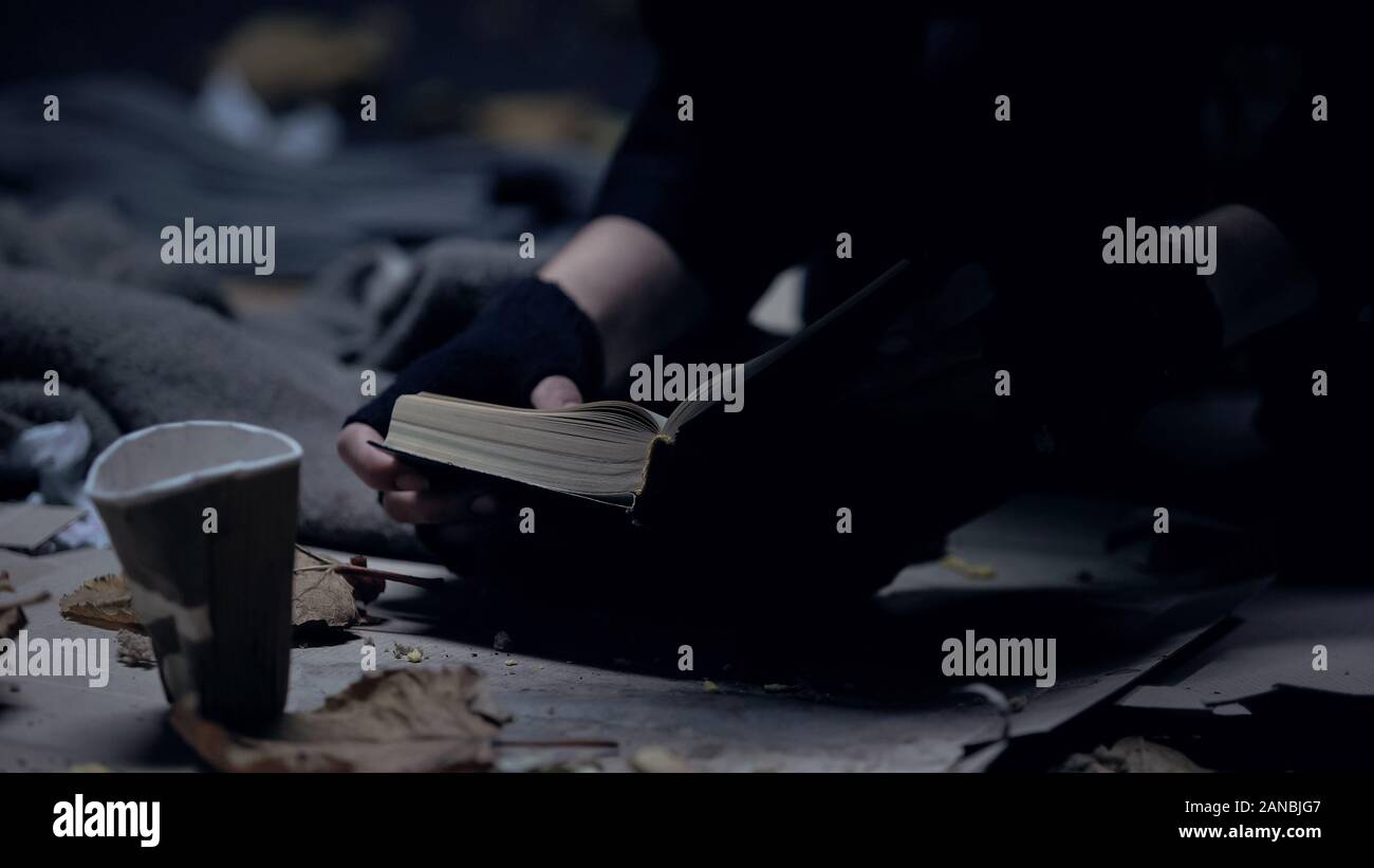 Poor homeless person sitting on ground reading bible, praying for ...