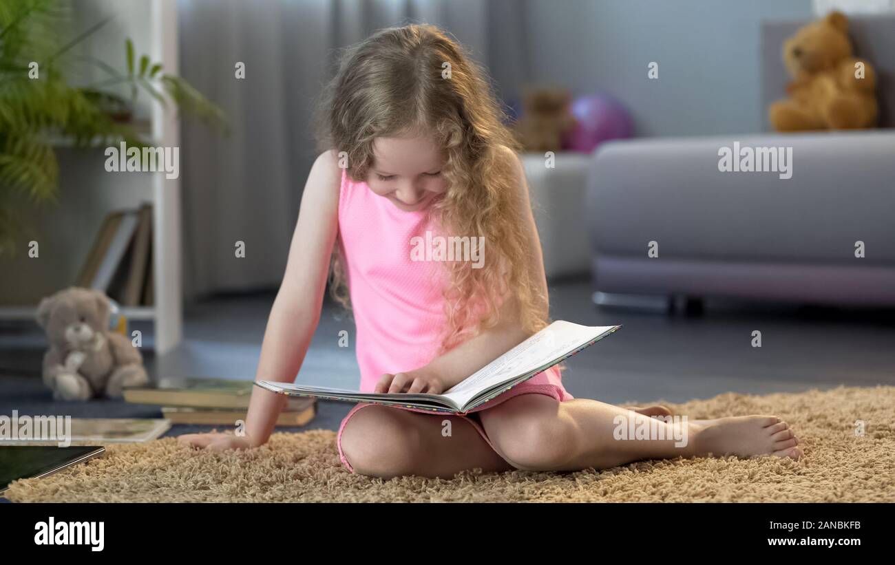 Little kid reading, laughing at funny story in childrens book, early ...