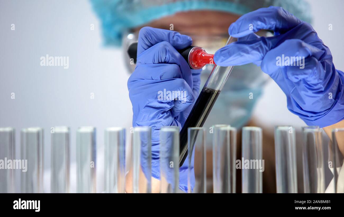 Scientist marking test tubes with black substance, controlling chemical ...