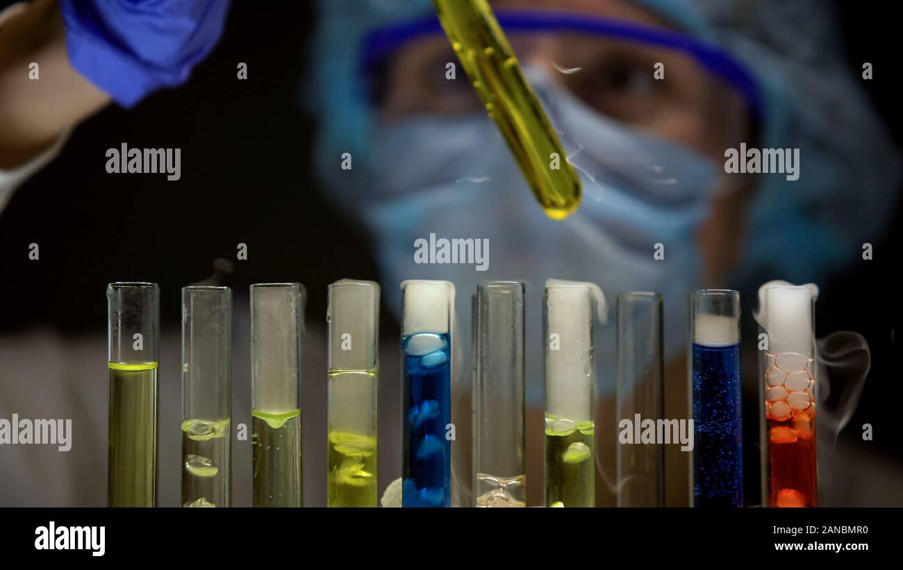Chemist checking sediment in tube with yellow liquid, substances ...