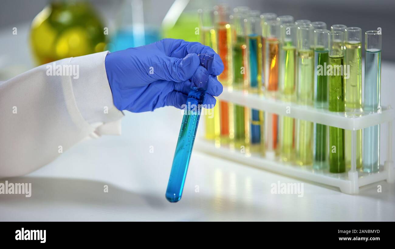 Lab assistant checking sediment in tube with blue liquid, washing ...