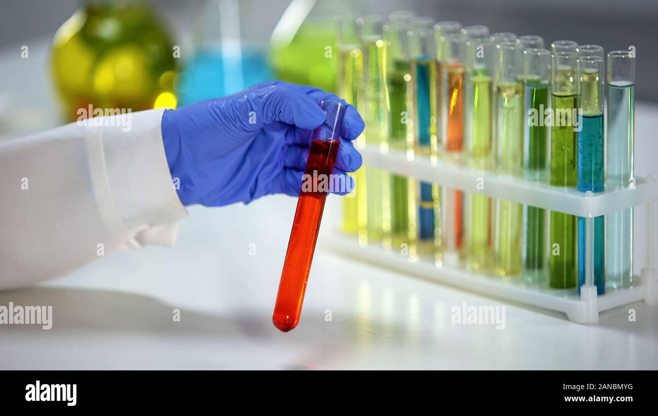 Chemist checking tube with orange liquid, dyestuff agent, washing ...